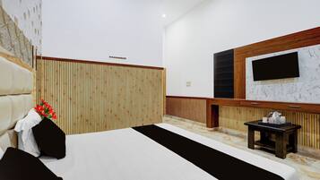 Quarto de hotel moderno com cama grande, painel de parede de madeira, televisão de tela plana e pequena mesa com bandeja.