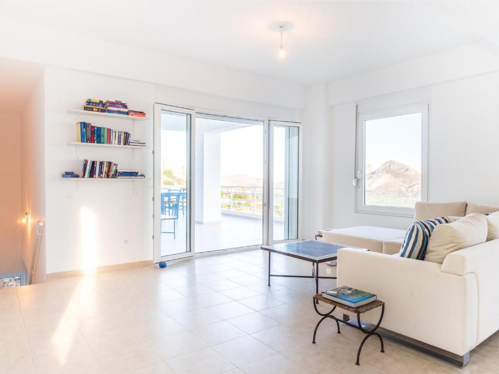 Uma sala de estar luminosa com um sofá branco, uma mesa de centro e uma estante.