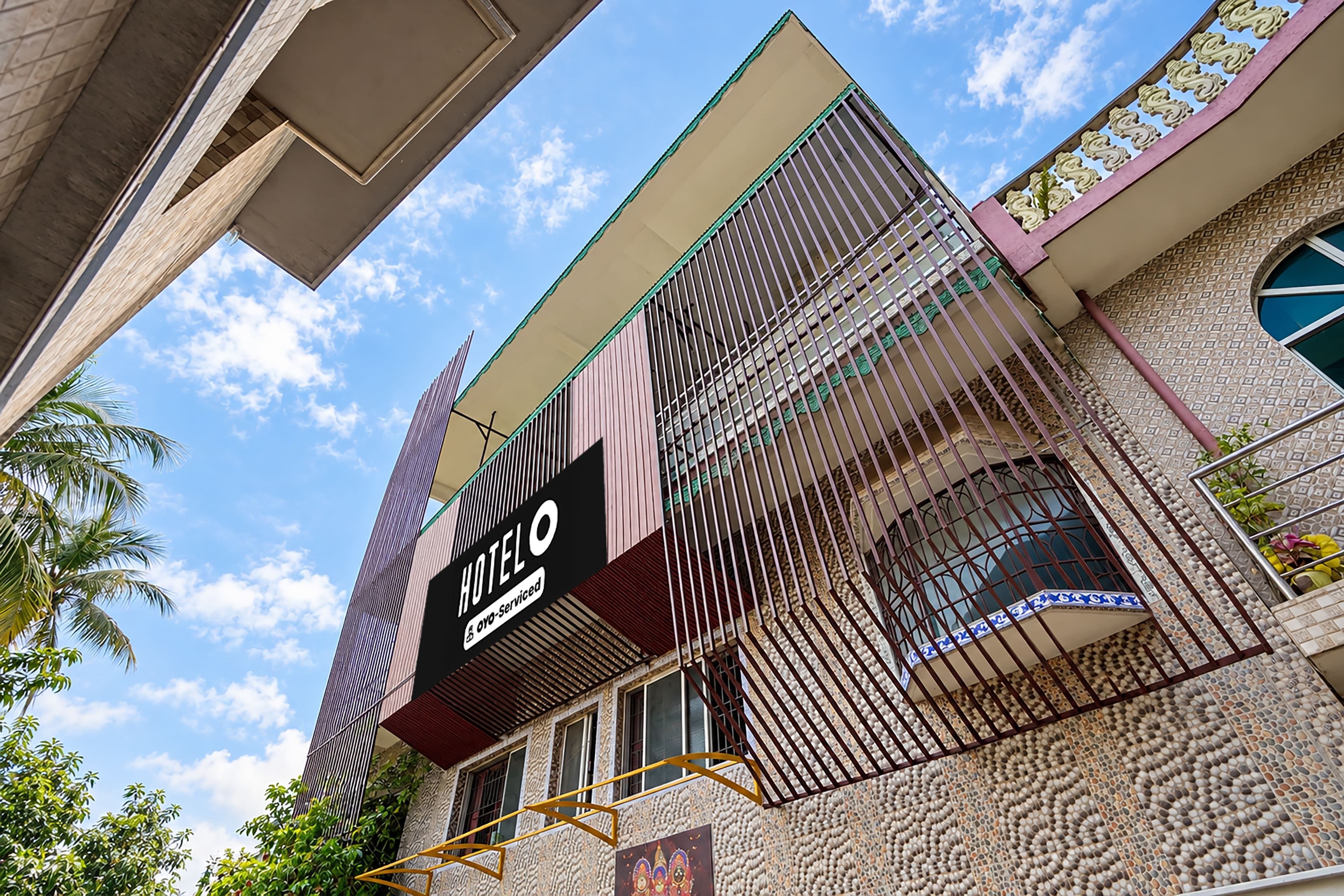 Um hotel com uma placa de destaque, varanda com grades de metal e fachada estampada.