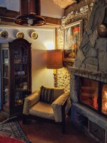 Uma sala de estar aconchegante com lareira de pedra, um armário de madeira e uma poltrona confortável.