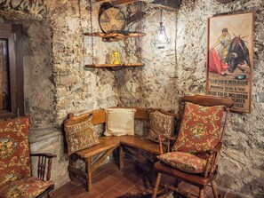 Decoração rústica com paredes de pedra, móveis de madeira e um candeeiro tradicional.