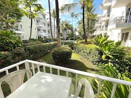 Pátio de hotel com piscina, palmeiras e sebes bem cuidadas.