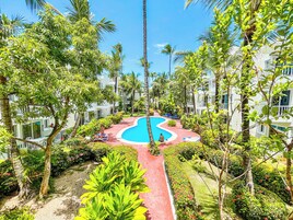 Um resort com piscina central, cercado por vegetação exuberante e palmeiras.