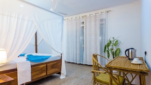 Quarto com cama, mesa com chaleira, cadeira e planta.