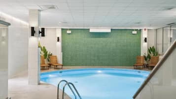 Piscina interna com parede azulejada, espreguiçadeiras e uma escadaria.