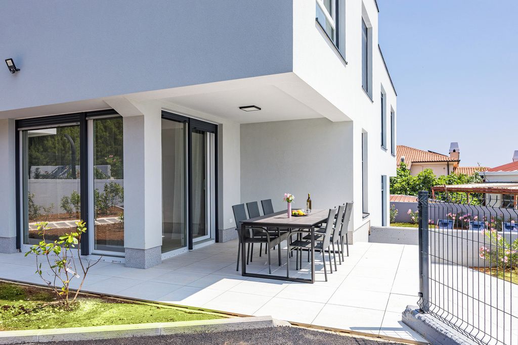 Uma casa moderna com um pátio, uma mesa de jantar e cadeiras.