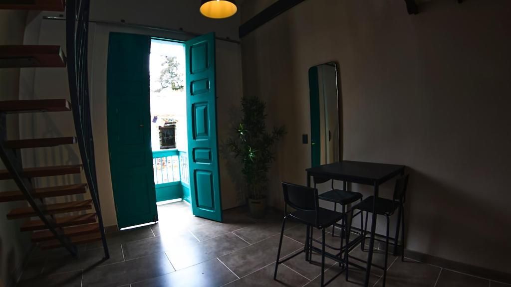 Quarto com uma mesa de jantar e cadeiras, um lance de escadas e uma porta que dá para o exterior.