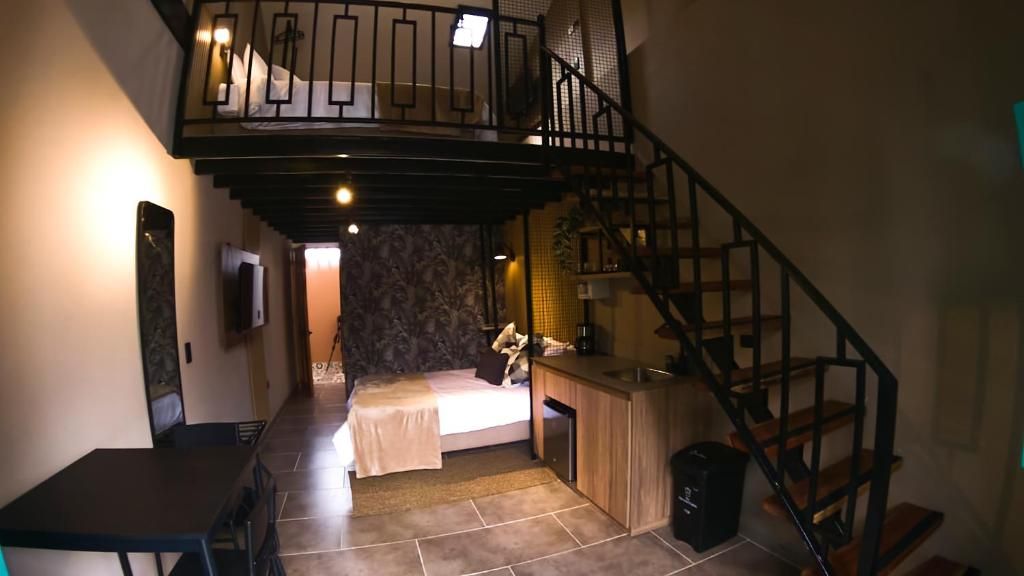 Um espaço de estar compacto com cama, pequena cozinha, área de refeições e escada para um andar superior.