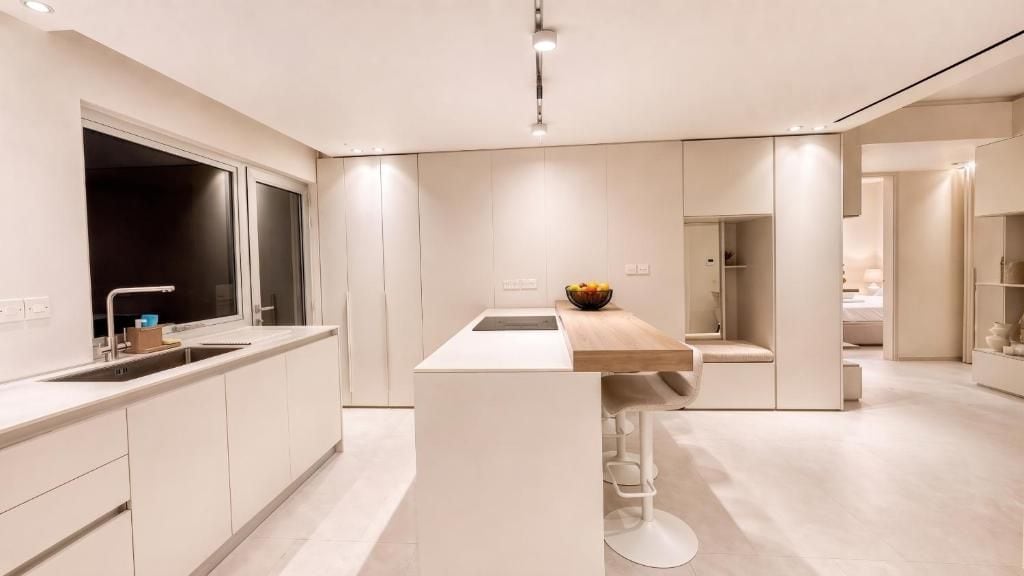 Uma cozinha moderna com ilha central, armários brancos e uma janela.