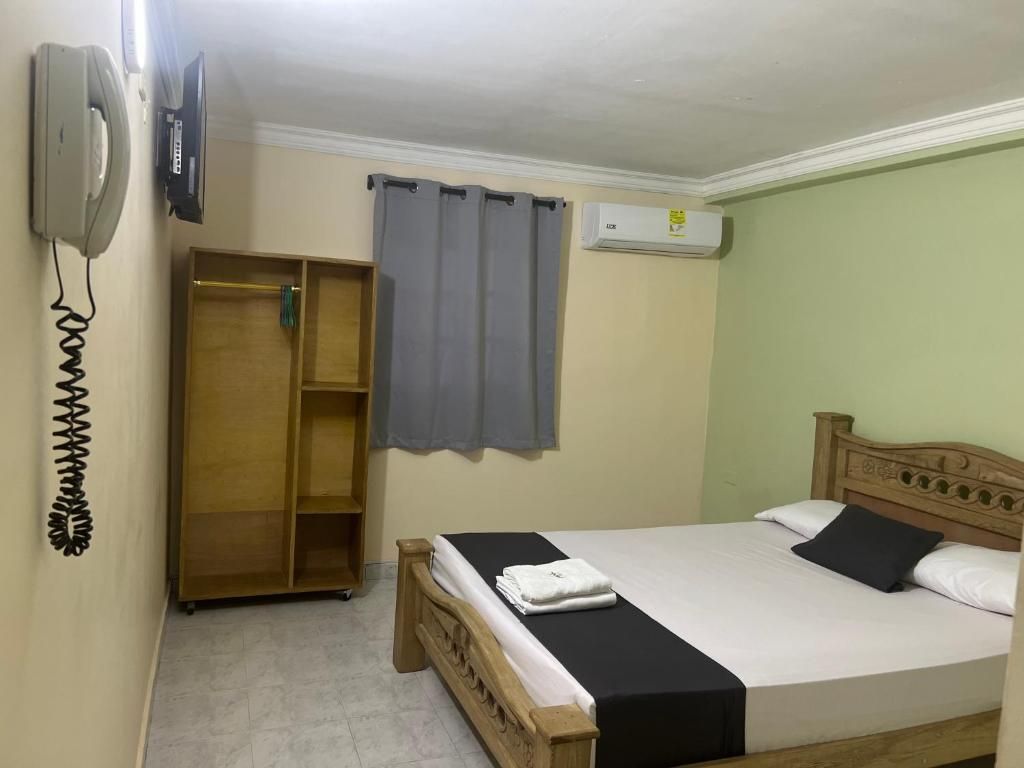Quarto com cama, guarda-roupa, telefone e ar condicionado.