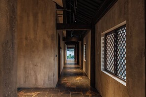 Um corredor com soalho em azulejos e uma janela com padrão de treliça.
