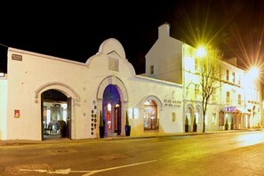 Um edifício com fachada branca, várias arcadas e uma placa com a inscrição 'BLUE VEN'.