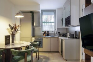 Uma cozinha moderna com área de refeições, incluindo uma mesa com cadeiras, uma luminária pendente e uma janela com vista.