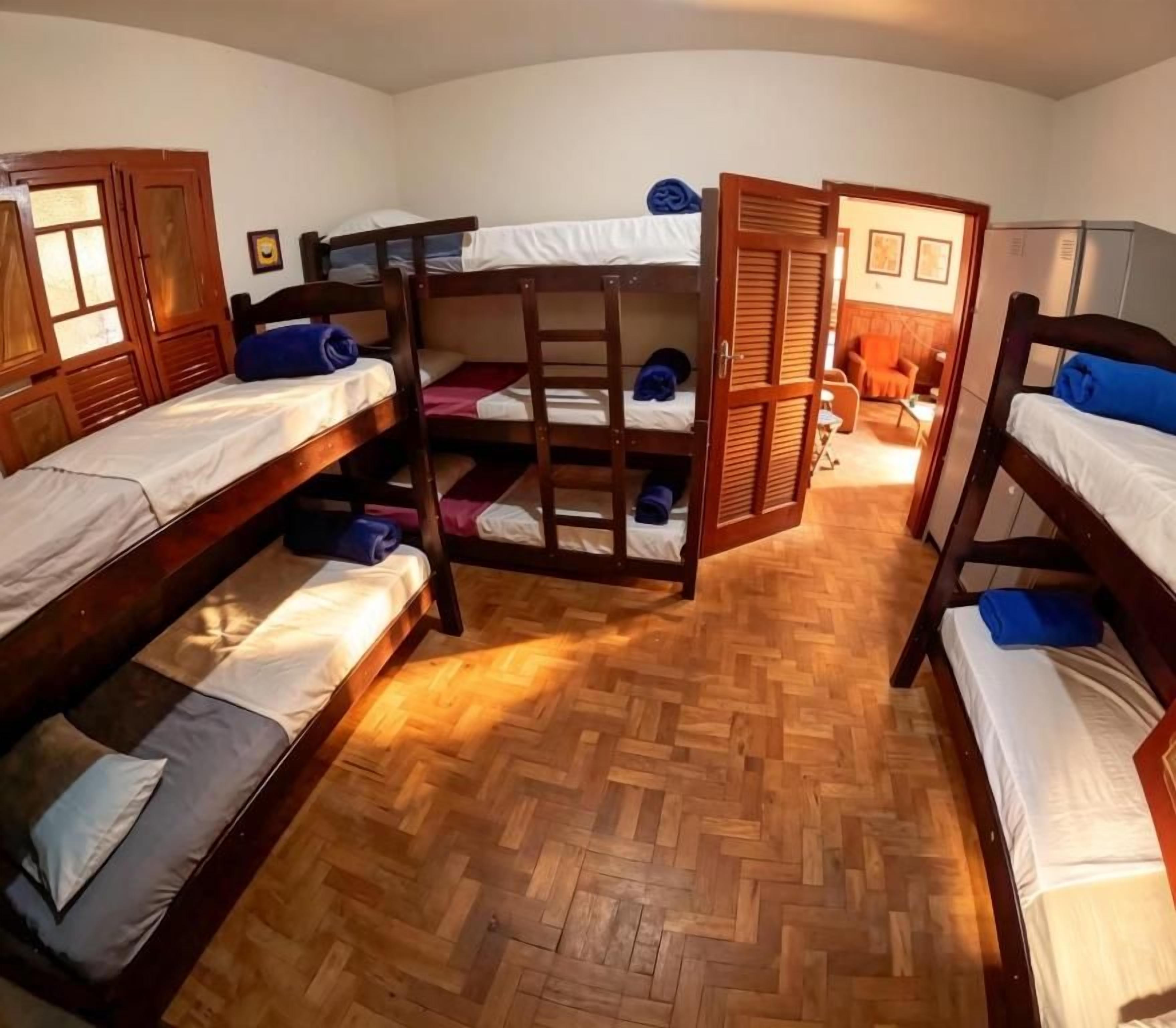 Quarto com beliches, piso de madeira e guarda-roupa.