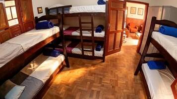 Quarto com beliches, piso de madeira e guarda-roupa.