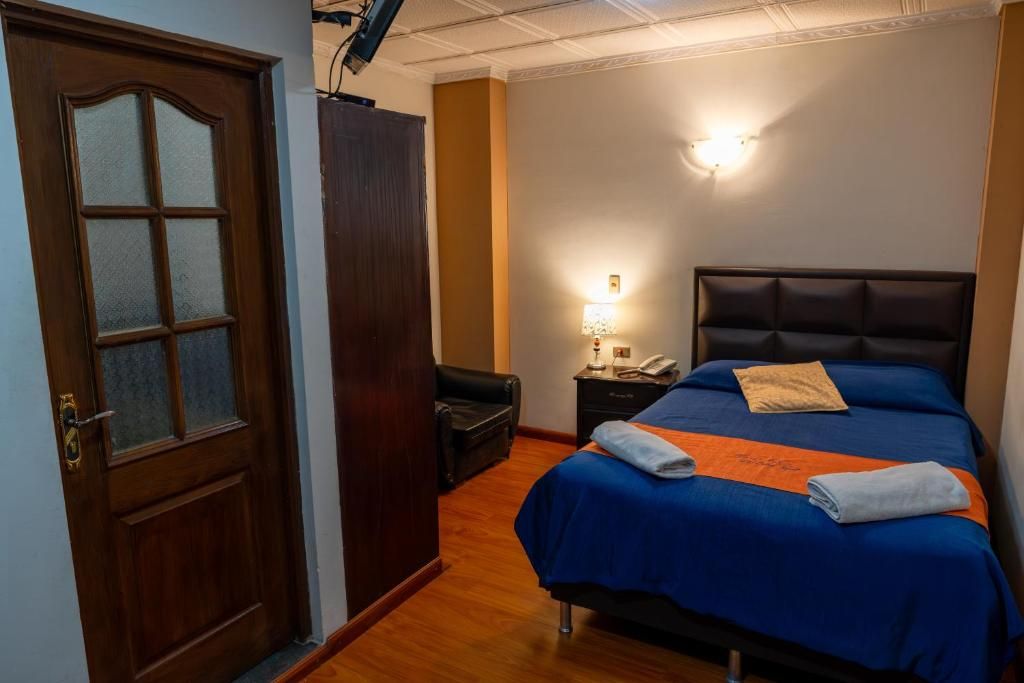 Quarto com cama, mesa de cabeceira, abajur, guarda-roupa e porta.
