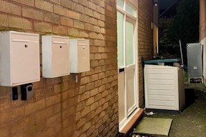 Edifício de tijolos com três contadores de serviços instalados na parede e uma porta branca.