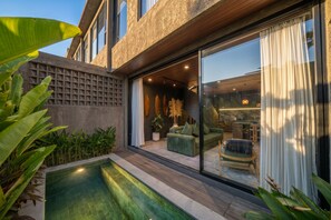Uma casa moderna com piscina, portas de correr e interior acolhedor com sofá e área de jantar.