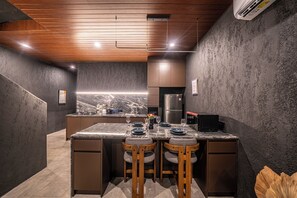 Cozinha moderna com bancada de mármore, banquetas de madeira e geladeira embutida.