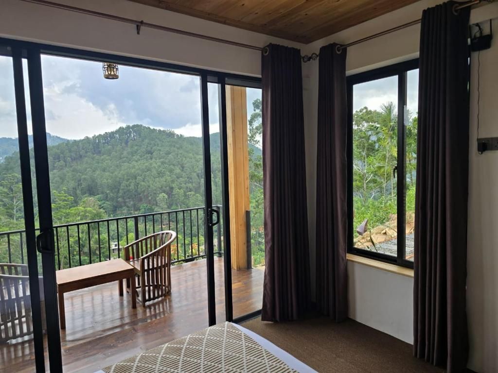Quarto com uma grande porta de vidro deslizante que dá para uma varanda com vista para uma encosta arborizada.
