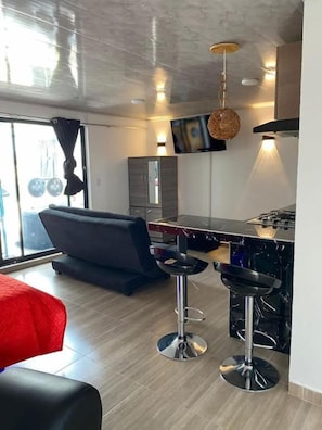 Uma cozinha moderna com bancada de mármore, dois banquetes e um espaço de refeições com um sofá.