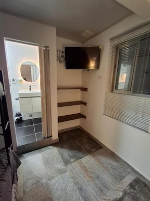 Interior moderno com TV de tela plana na parede, escada e janela com persianas.