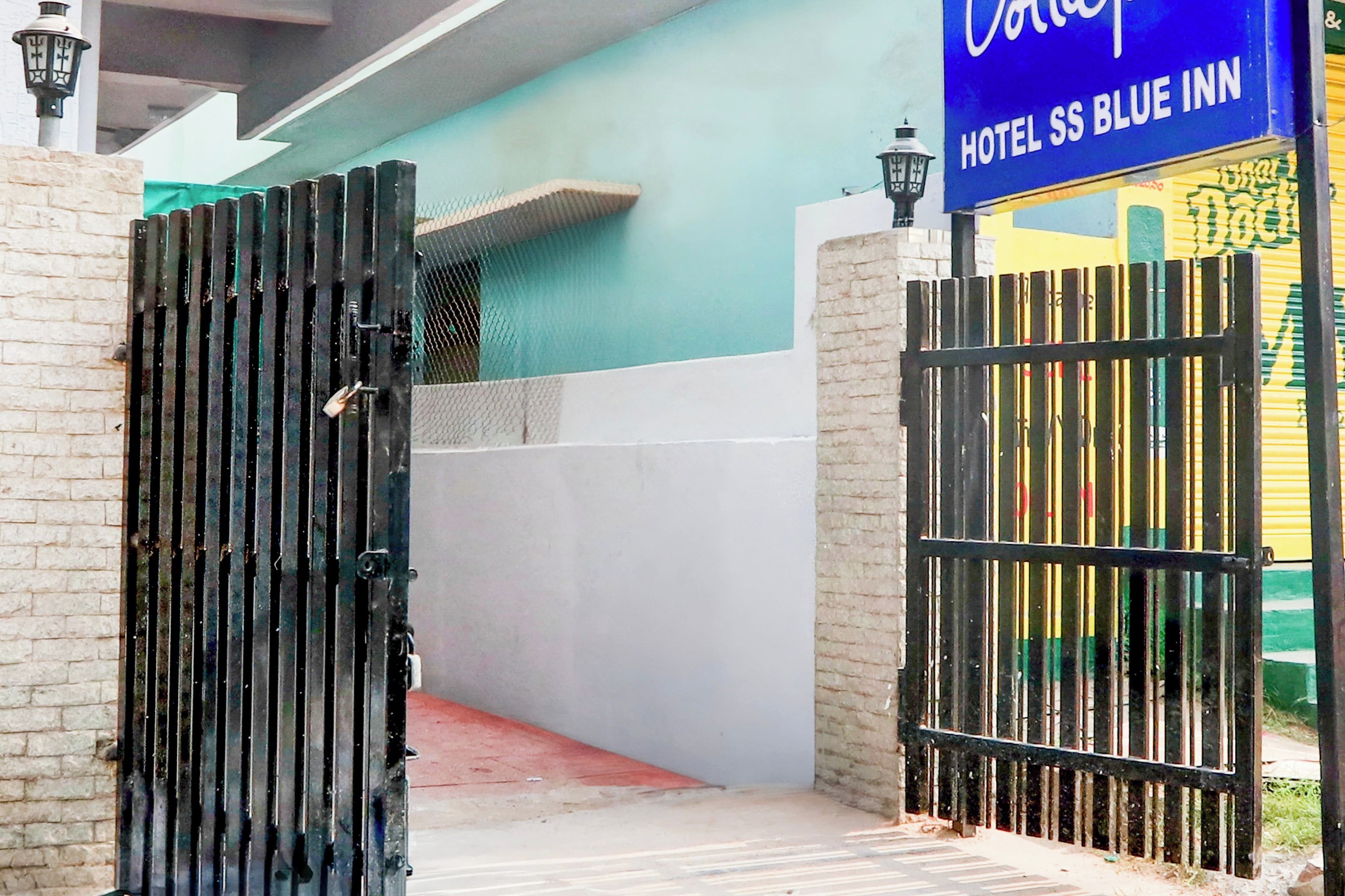 Uma entrada com portão para um hotel, com uma placa azul em cima.