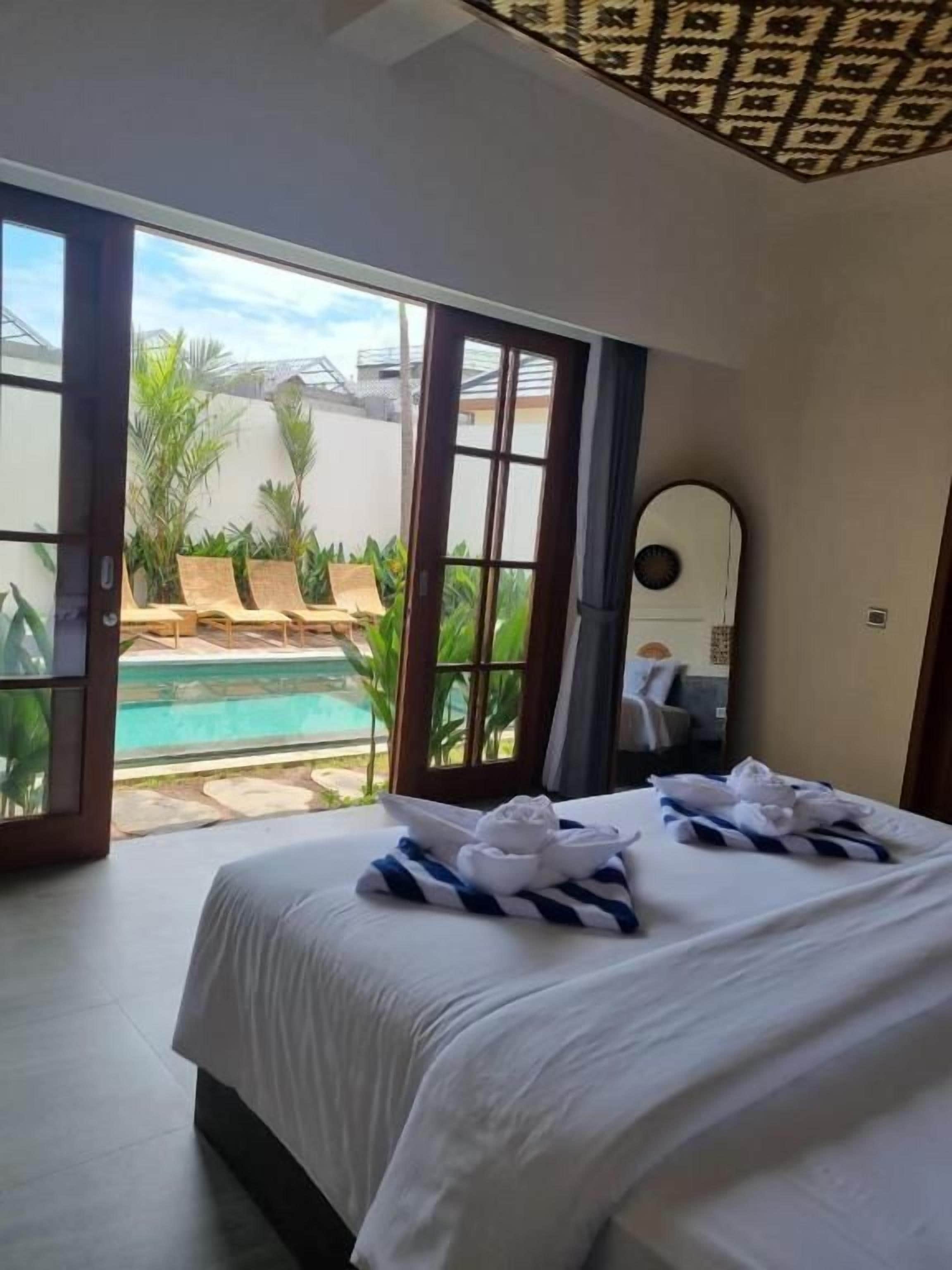 Quarto de hotel com cama, uma janela grande e vista para uma piscina.
