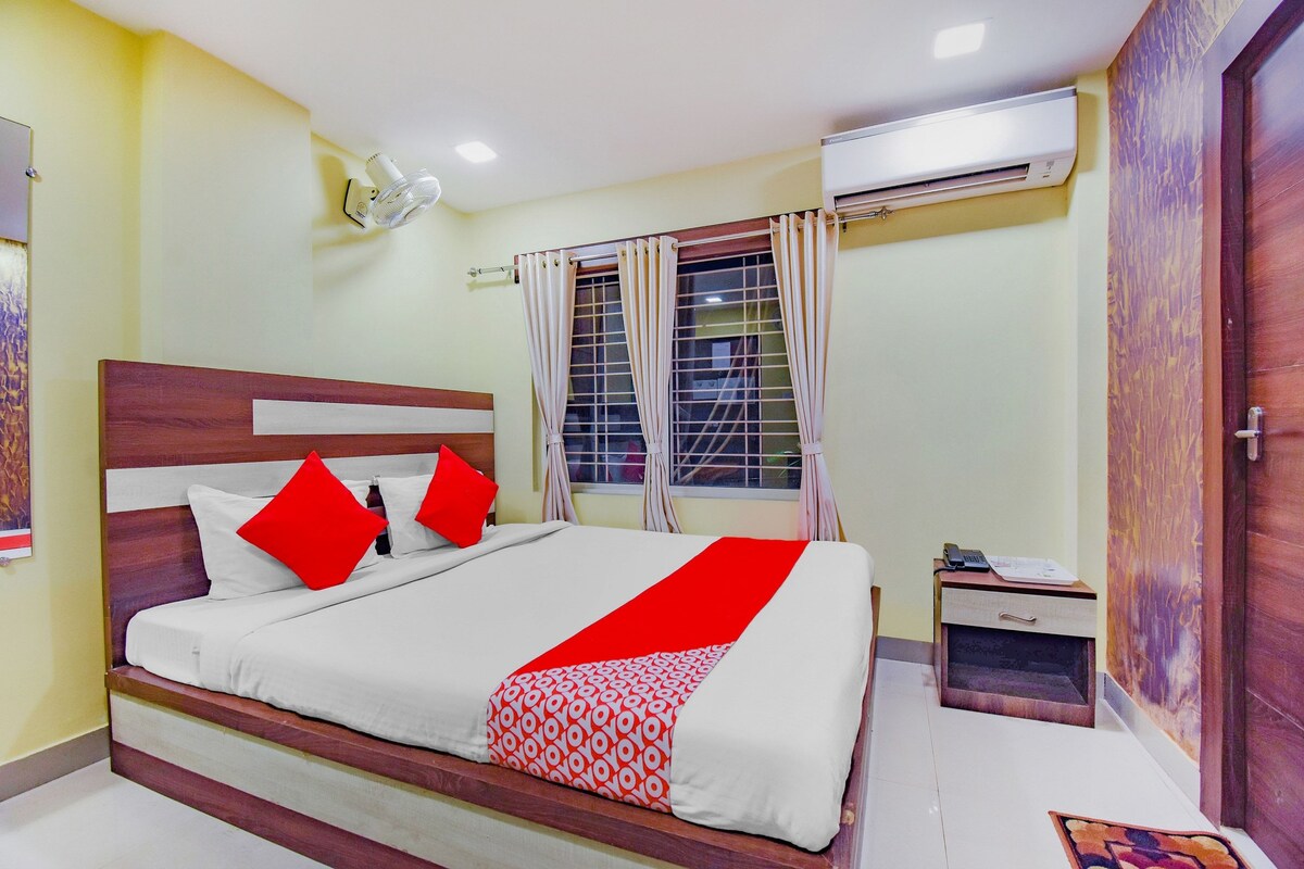 Quarto de hotel com cama, mesa de cabeceira, aparelho de ar condicionado e guarda-roupa.