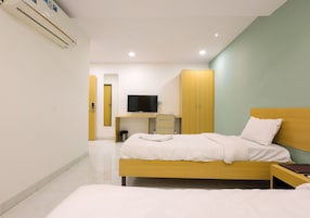 Quarto de hotel com cama, televisão, escrivaninha e guarda-roupa.