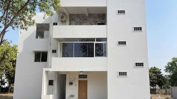 Um edifício moderno de dois andares com fachada plana, grandes janelas e entrada central.