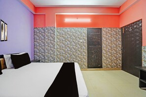 Quarto de hotel com cama, guarda-roupa e banheiro com espelho e pia.