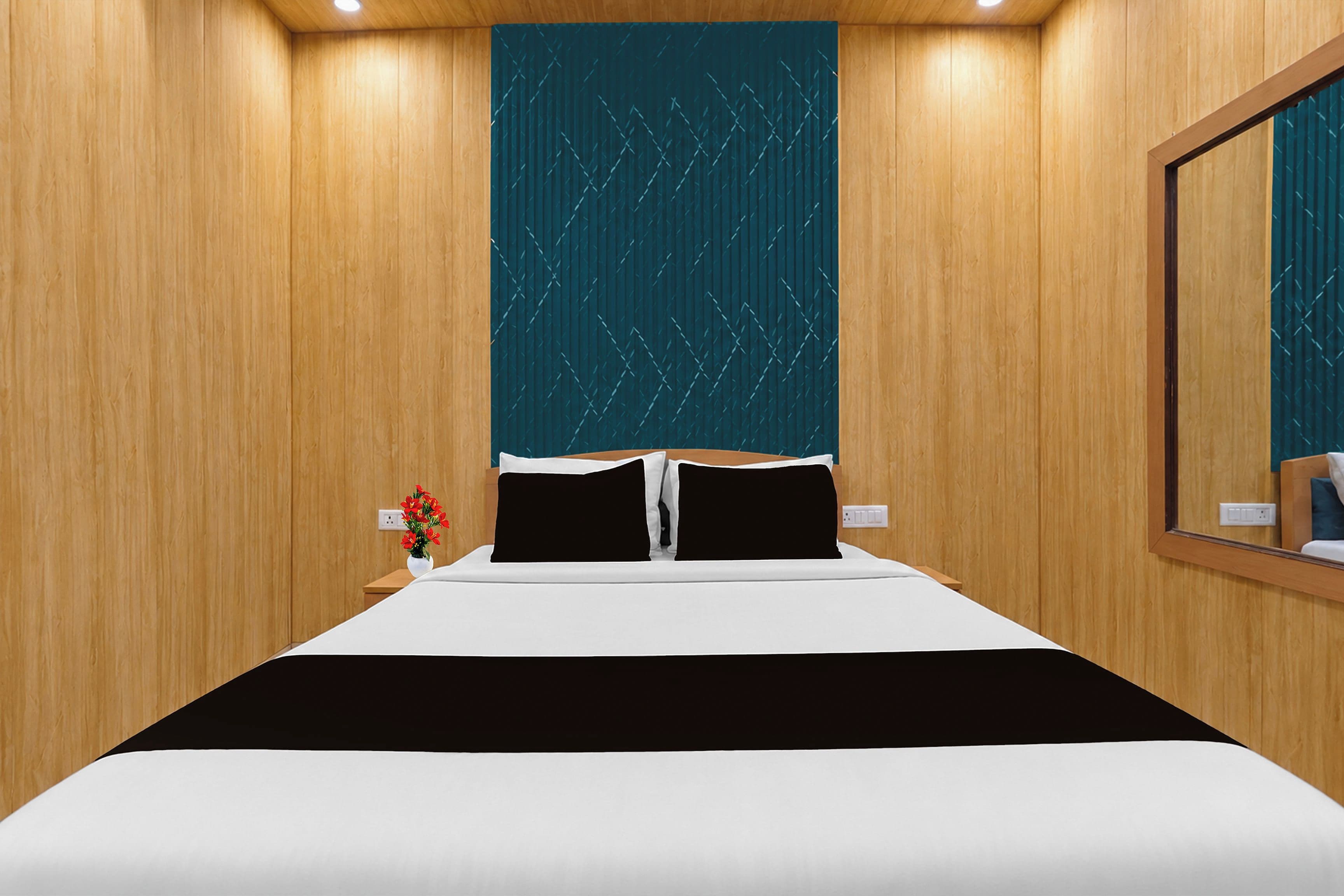 Quarto de hotel com cama grande, paredes de madeira, parede com padrão azul-esverdeado e um espelho.