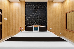 Quarto de hotel com uma cama grande, paredes de madeira, um painel decorativo e uma mesinha de cabeceira com um vaso de flores.