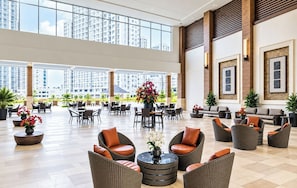 Amplo espaço interno com diversas opções de assento, uma grande janela com vista para edifícios altos e design de interiores moderno.