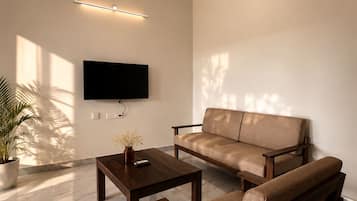 Uma sala de estar moderna com sofá, mesa de centro, TV na parede e ventilador de teto.