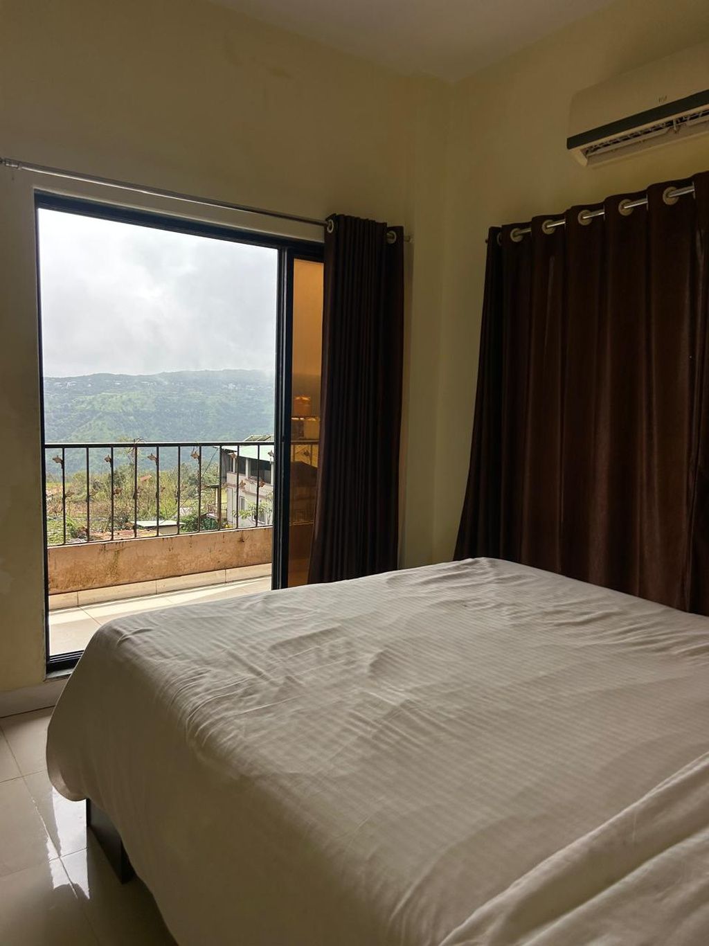 Quarto de hotel com cama, vista para o exterior e janela com cortinas.