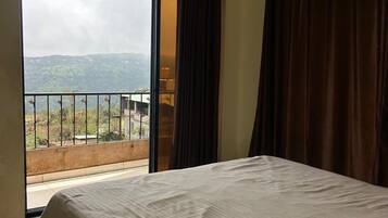 Quarto de hotel com cama, vista para o exterior e janela com cortinas.