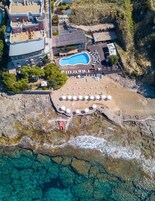 Vista aérea de um resort com piscina, área de praia e costa rochosa.