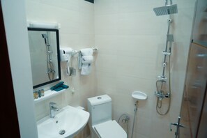 Uma casa de banho com lavatório, sanita e chuveiro.