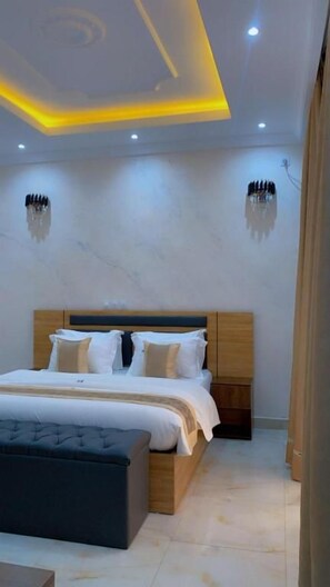 Quarto com cama, mesas de cabeceira e um design moderno no teto.