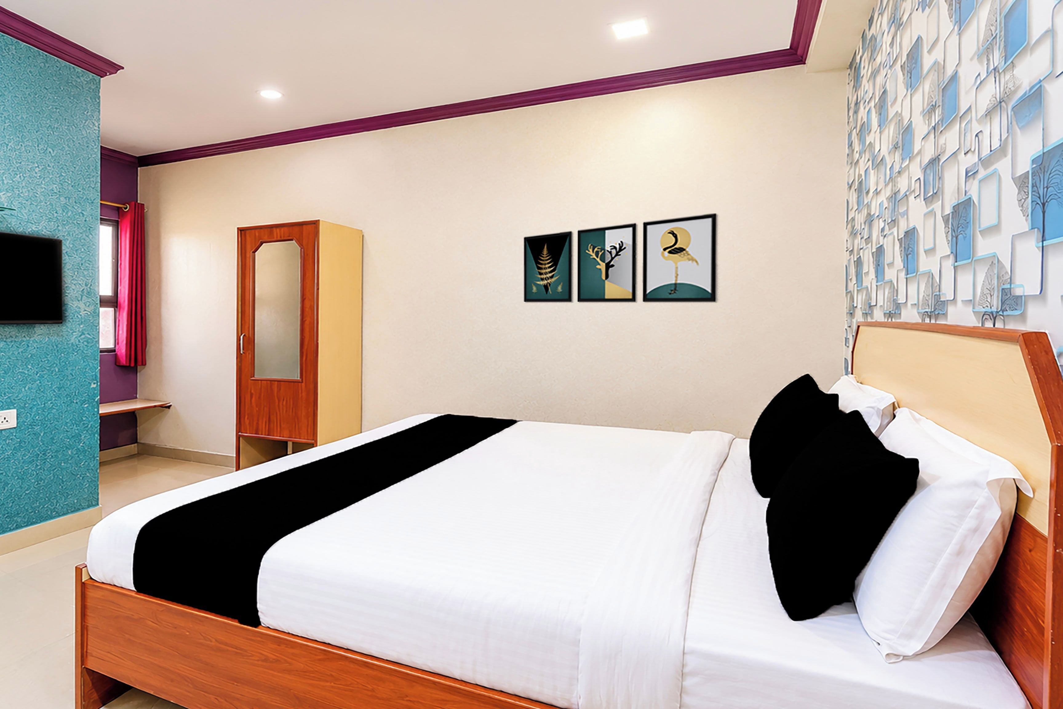 Quarto de hotel com cama, guarda-roupa, espelho e obras de arte na parede.