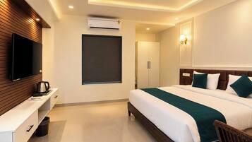 Quarto de hotel moderno com cama, televisão, guarda-roupa e ar condicionado.