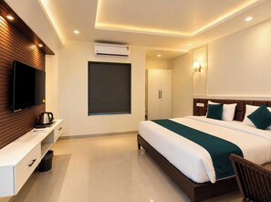 Quarto de hotel moderno com cama, televisão, guarda-roupa e ar condicionado.