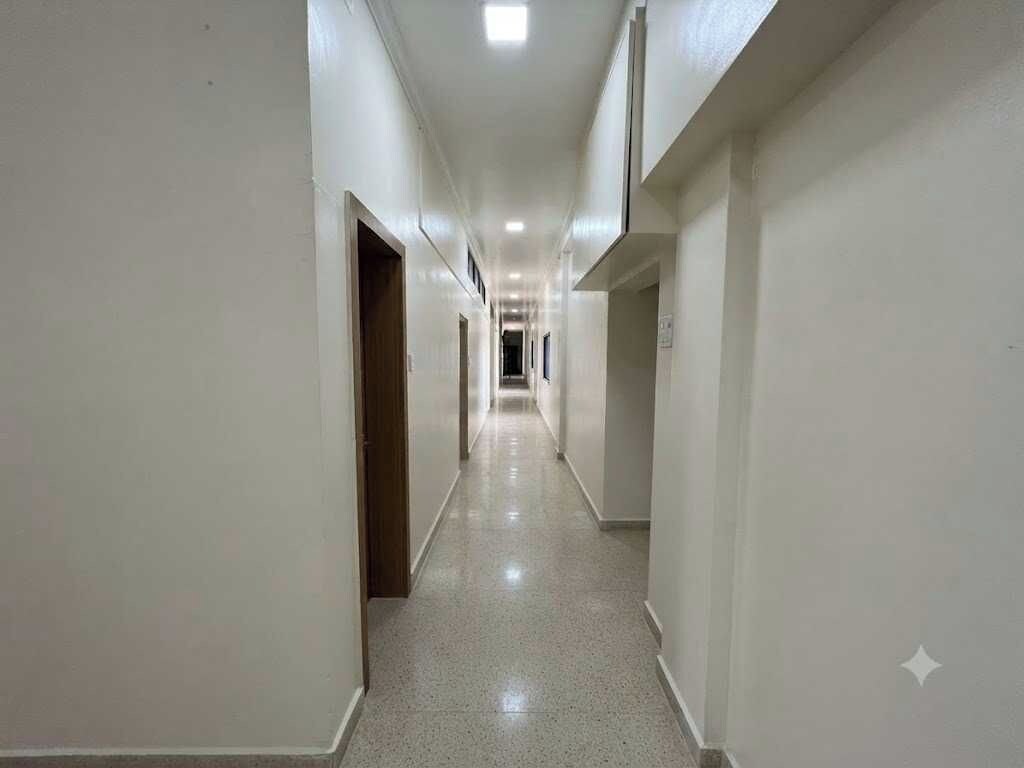 Um corredor comprido e estreito, com portas em ambos os lados, que dá acesso a quartos.
