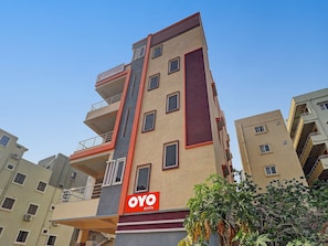 Edifício de vários andares com uma placa chamativa 'OYO ROOMS' na fachada.