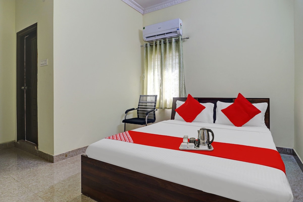 Quarto de hotel com uma cama, uma cadeira, ar condicionado e janela com cortinas.