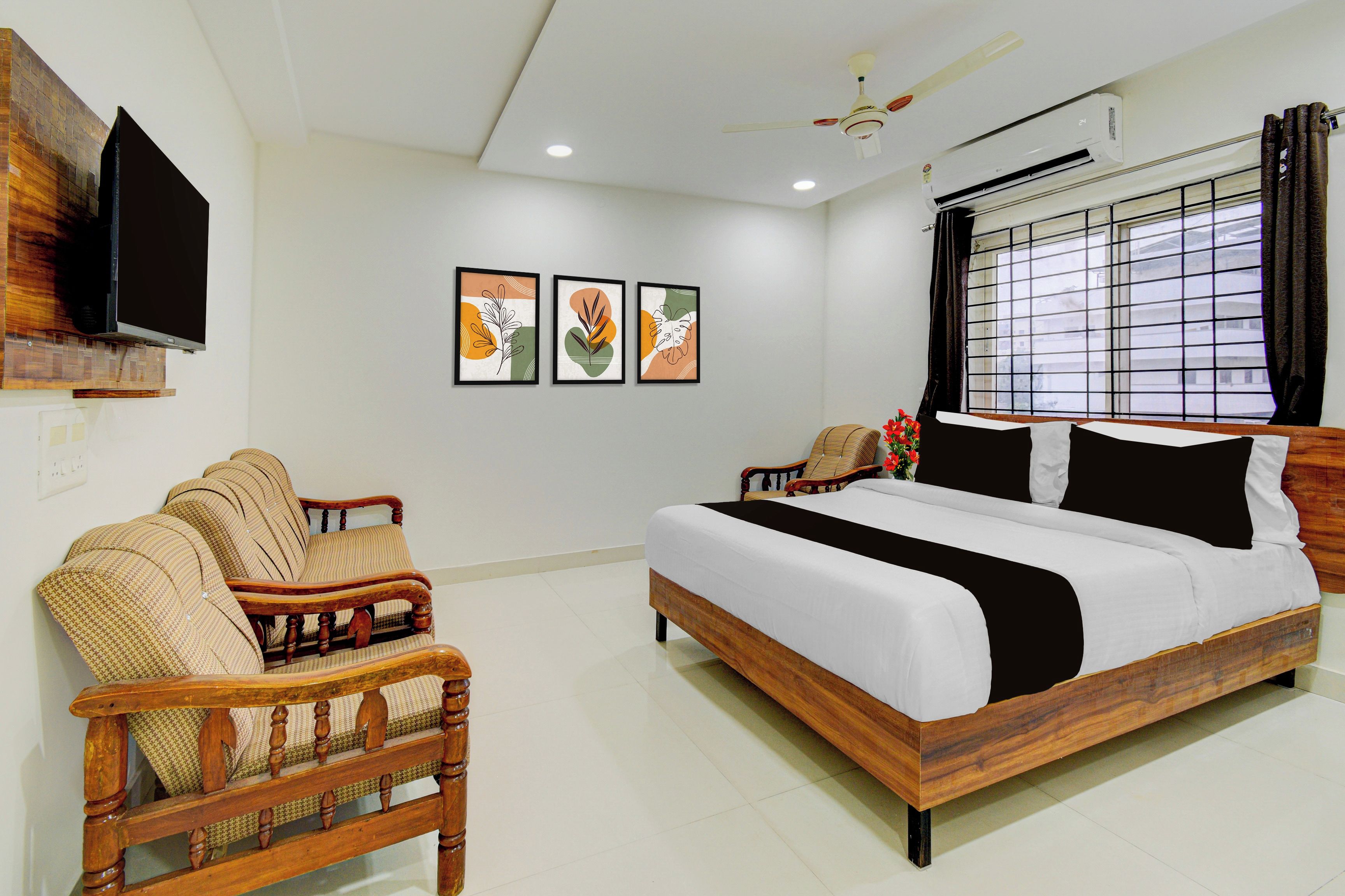 Quarto com cama, sofá, televisão e quadros nas paredes.
