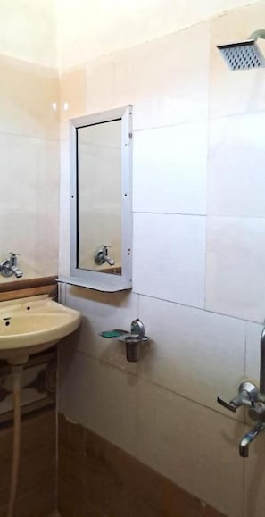 Uma casa de banho com lavatório, espelho e chuveiro.