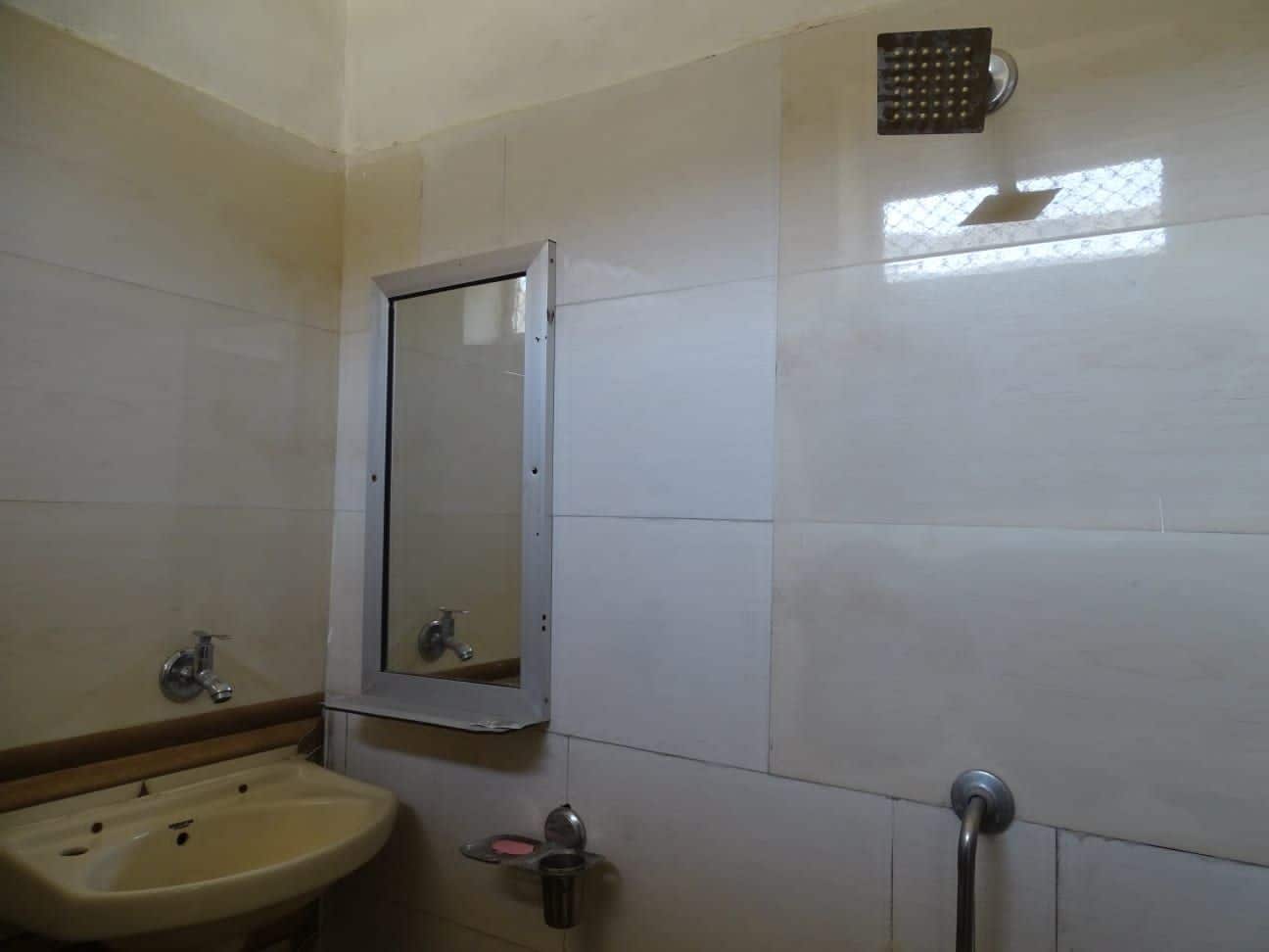 Casa de banho com lavatório, espelho e chuveiro.